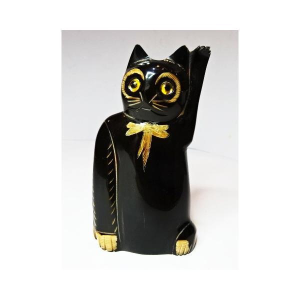 水牛の角の手彫り細工による招き猫です。黒い招き猫は厄除けに。さらに左手をあげている猫は人（客）を招くとか。蝶ネクタイをしめた愛らしい造形です。横6.0cm　高さ10.8cm　厚み（幅）3.4cm。タイ製