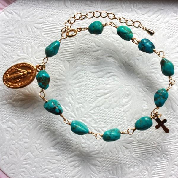 半貴石ターコイズ（スタビライズ加工）使用。金色「不思議のメダイ」（イタリア製）と十字架のチャーム付き長さ：約１８センチ アジャズター付き＊スタビライズ加工とは、天然ターコイズの変色や壊れを避けるために樹脂加工をすることです。