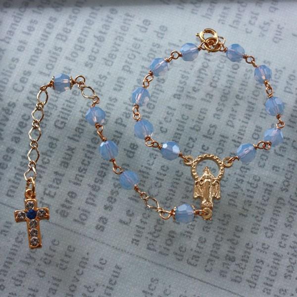 スワロフスキー＃5000 6mm エアーブルーオパール使用。金色クロスにはキラキラ付きです。センターパーツは無原罪のマリア様(金色)長さ：約17cm〜20cm アジャスター付き