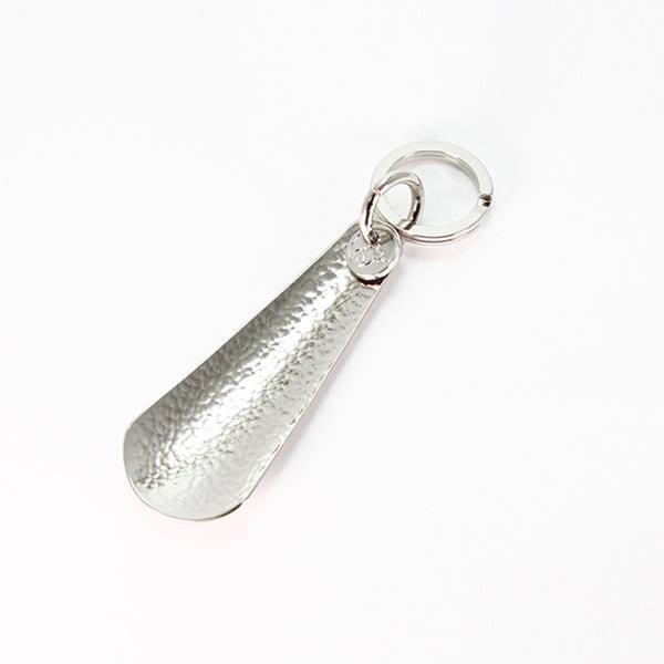 日本の職人が丹念に打ち出し加工を施した真鍮製シューホーン。鍛えることで強度を増したシューホーンは乱反射する黄金色の光をまとうように存在感を放ちます。古くから用いられてきた伝統技法をデザインに昇華させた意匠をもつキーリング付きのシンプルなポケ...