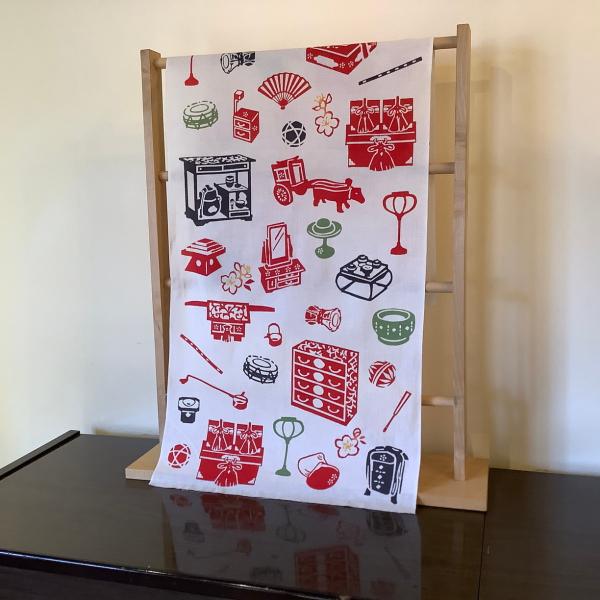 てぬぐい「雛道具」和テイストの情緒あふれるてぬぐいです。薄いピンク地の配色です。手ぬぐいタペストリーでお雛様飾りをアレンジ！まるで本物のように細かな意匠で細部まで精巧に作られた数々の雛道具。気品溢れる小さな小さな調度類は、春の訪れを華やかに...