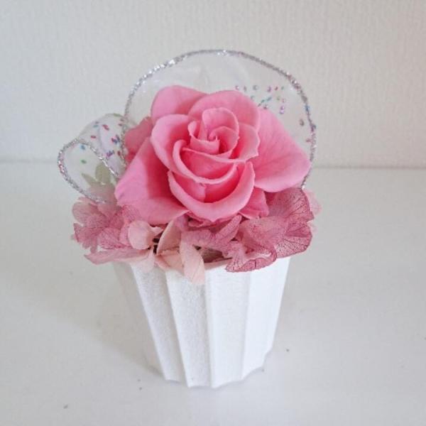 プリザーブドフラワーのアレンジメントです。こちらは「シュガーピンク(薄い)」です。キラキラしたレインボーオーガンジーをまとったローズ一輪アレンジです。ほんの気持ちのご挨拶の一品に喜ばれています。器はプラスチック花器です。アレンジ W9×D8...