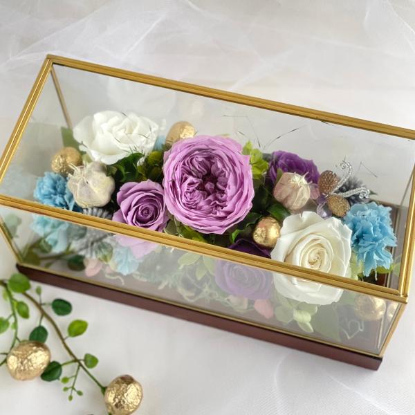 プリザーブドフラワーアレンジです。【商品説明】パープルカラーのお花を中心に華麗な雰囲気のするゴールド枠のガラスケースに入ったアレンジメントです。四方見のアレンジですので、テーブルの中央に置いても楽しんでいただけます。お誕生日、新築、ご結婚祝...