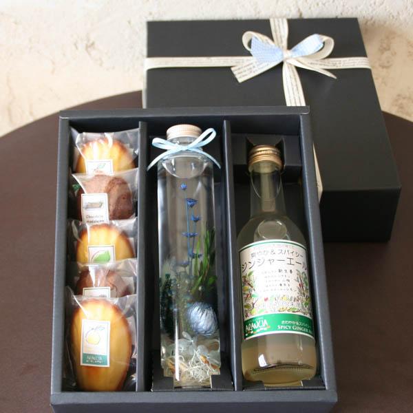 標本風お花のアレンジ「ハーバリウム」に、和歌山産柑橘フルーツを焼き込んだマドレーヌ2〜3種で5個、当店カフェオリジナルのジンジャーエールもしくはオレンジジュースを添えて、クールな黒い箱(約25cm×22cm）に入れたオシャレなギフト。お花に...