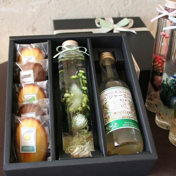 標本風お花のアレンジ「ハーバリウム」に、和歌山産柑橘フルーツを焼き込んだマドレーヌ2〜3種で5個、当店カフェオリジナルのジンジャーエールもしくはオレンジジュースを添えて、クールな黒い箱(約25cm×22cm）に入れたオシャレなギフト。お花に...