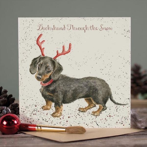 "Daschund Through the Snow"（雪の中を駆け回るダックスフンド）クリスマスソング「ジングルベル」の冒頭の歌詞、"Dashing through the snow"をもじったモチーフ。赤いトナカイのツノを付けた可愛らし...