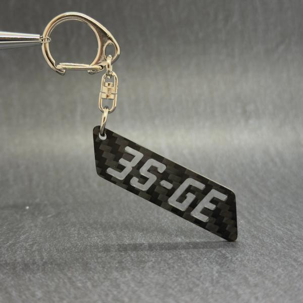 ドライカーボン製のエンジン型式キーホルダーです。*剥離防止のため、切削面は保護材を塗っています*受注生産品になります。*一部イメージ画像になります・石留め参考画像のように右下にカラーキュービックジルコニアを留めることも可能です。・キーホルダ...