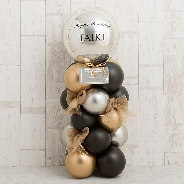 マットなゴールド、ブラック、シルバーのバルーンでスタンディングの土台を作り、アクセントに違う質感のリボンをオン。マットなバルーンと、キラキラとしたバルーンに程よく馴染む、抜け感のあるアレンジです。トップには、まんまる大きなミラーのようなバル...