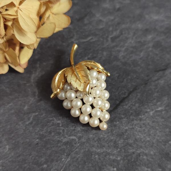 ■sizeW2.7cm×H4.2cm　厚さ1.2cmコスチュームジュエリー界で最も著名なTRIFARIのヴィンテージブローチ。葡萄を表現したふっくらと房状に連なるパールが、瑞々しさと上品な華やかさを添えています。ゴールドトーンのリーフと蔓は...