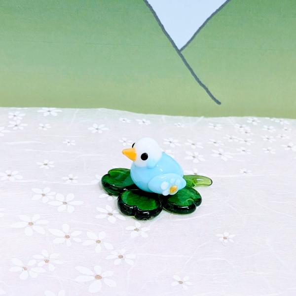 花インコ（青）とよつばのガラス細工の置物です。【大きさ】約高さ１８ミリ　　横幅２３ミリ　　　　　奥行３０ミリ＊商品は一つ一つ手造りのため大きさや色合いなどが写真と異なる場合がありますのでご了承をお願い致します。