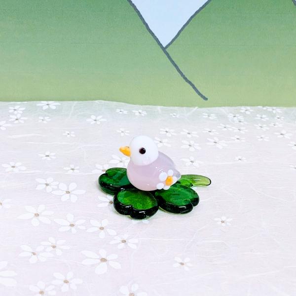 花インコ（桃）とよつばのガラス細工の置物です。【大きさ】約高さ１８ミリ　　横幅２３ミリ　　　　　奥行３０ミリ＊商品は一つ一つ手造りのため大きさや色合いなどが写真と異なる場合がありますのでご了承をお願い致します。