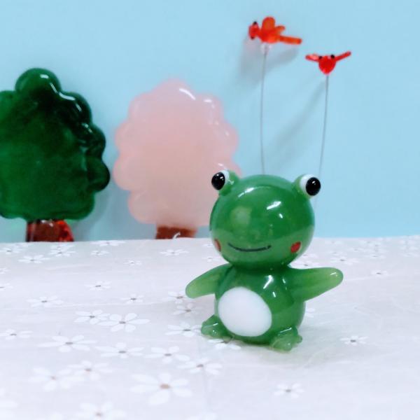 カエル（手上げ）のガラス細工の置物です。【大きさ】約高さ２６ミリ　　横幅２６ミリ　　　　　奥行１６ミリ＊商品は一つ一つ手造りのため大きさや色合いなどが写真と異なる場合がありますのでご了承をお願い致します。