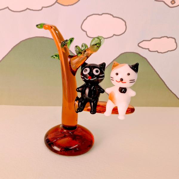 ネコペアと木（クロ/ミケ）のガラス細工の置物です。【大きさ】約高さ７０ミリ　　横幅６０ミリ　　　　　奥行３２ミリ＊商品は一つ一つ手造りのため大きさや色合いなどが写真と異なる場合がありますのでご了承をお願い致します。