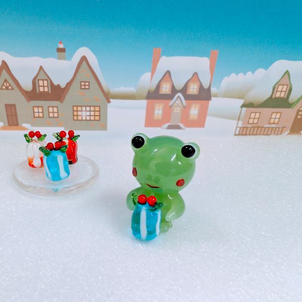 カエルとギフトボックス（青）のガラス細工の置物です。【大きさ】約高さ２４ミリ　　横幅１５ミリ　　　　　奥行２０ミリ＊商品は一つ一つ手造りのため大きさや色合いなどが写真と異なる場合がありますのでご了承をお願い致します。