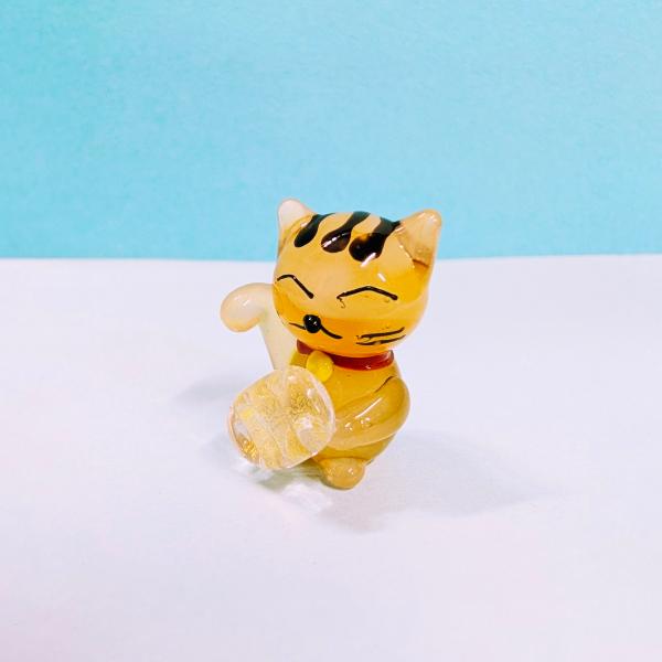 招き猫（茶トラ）と小判（金箔入）のガラス細工の置物です。【大きさ】約高さ２３ミリ　　横幅１８ミリ　　　　　奥行１８ミリ＊商品は一つ一つ手造りのため大きさや色合いなどが写真と異なる場合がありますのでご了承をお願い致します。