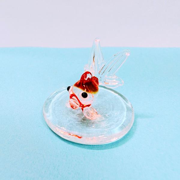 金魚（M)クリア（丸台付）のガラス細工の置物です。【大きさ】約高さ３０ミリ　　横幅３５ミリ　　　　　奥行３５ミリ＊商品は一つ一つ手造りのため大きさや色合いなどが写真と異なる場合がありますのでご了承をお願い致します。