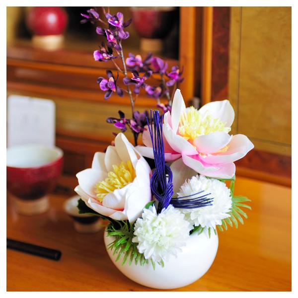 仏壇や遺影に添えるお供え花を造花でアレンジメントしました。仏花の象徴白菊の上に咲かせた薄ピンクの花は「ハスの花」です。泥水が濃ければ濃いほど、はすの花は大輪の花を咲かせます。泥水とは人生におきかえれば、つらいこと、悲しいこと、大変なこと。仏...