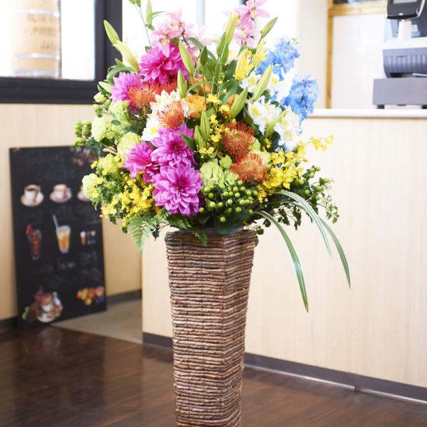 一般的なスタンド花とはひと味違った稀少花材で仕立てるスクエアスタンド式のスタンド花です。明るくポップな色彩の様々なカラーの稀少花材を利用、オーソドックスな4本脚のスタンドではなくバナナリーフを編んで作ったスクエアタイプの脚に、カラフルで見栄...