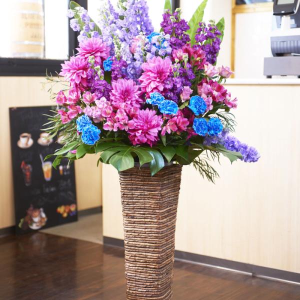 一般的なスタンド花とはひと味違った稀少花材で仕立てるスクエアスタンド式のスタンド花です。明るくポップな色彩の様々なカラーの稀少花材を利用、オーソドックスな4本脚のスタンドではなくバナナリーフを編んで作ったスクエアタイプの脚に、カラフルで見栄...