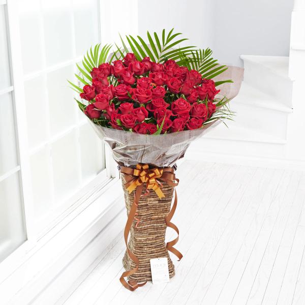 皇室献上実績のある農園で生産した新鮮なバラを利用、オーソドックスな4本脚のスタンドではなくバナナリーフを編んで作ったお洒落なスクエアタイプの脚に仕立てた赤薔薇50本のスタンド花商品です。農林水産大臣賞をはじめ、数々の受賞歴がある生産者が育て...