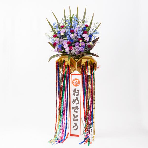 お祝いのシーンを盛り上げる存在感のあるくす玉が付いた、思わず目に留まる派手なスタンド花です。ゴールドのくす玉を割ると、カラフルな銀テープと一緒に「祝おめでとう」と書かれた紅白の垂れ幕が垂れ下がるお祝い花にふさわしい贈答用ギフトです。