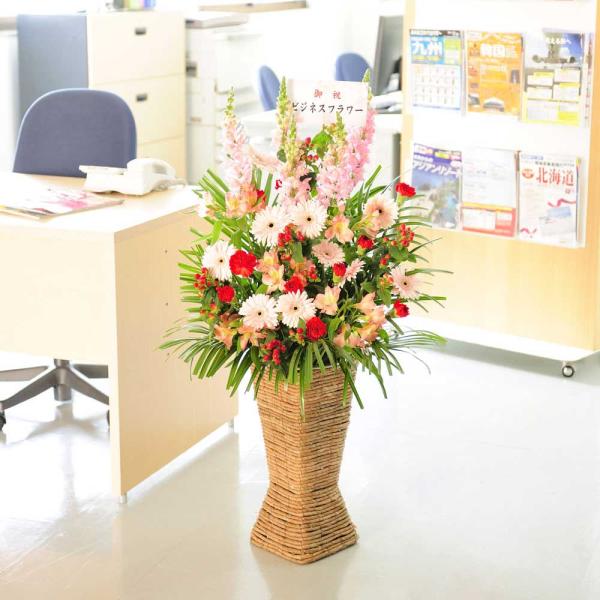 籐かごを思わせるスクエアタイプのスタンド花！（ロースタンド）スタンドは籐を編み込んだ様な使用となっており、和テイスト・アジアンテイスト感が強く、インパクトあるスタンドです。また、お花はゴージャスな雰囲気漂う赤色、可愛らしいイメージのあるピン...