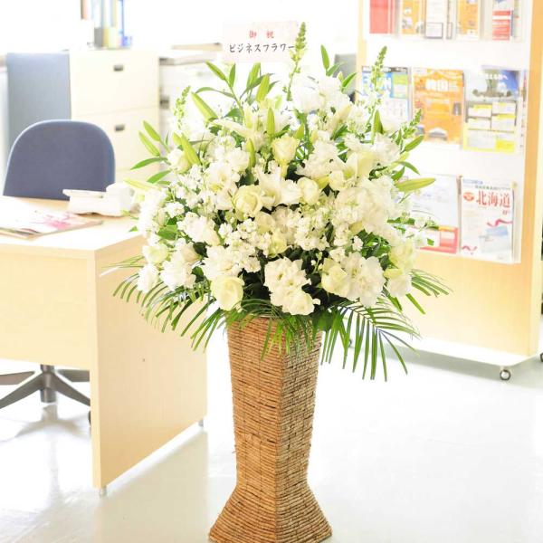 籐かごを思わせるスクエアタイプのスタンド花！（ミディアムスタンド）お花は清潔、清楚な雰囲気漂う白系で統一しており、設置スペースをより明るく演出してくれます。開店祝いや開業祝いに利用されるスタンドタイプのお花です。他のスタンド花と比べ、籐を編...