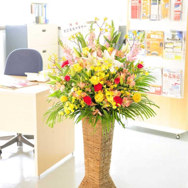 籐かごを思わせるスクエアタイプのスタンド花！（ミディアムスタンド）お花はその季節に合わせて旬なお花を中心に、色鮮やかに、ボリューム感を出し、ご用意しております。開店祝いや開業祝いに利用されるスタンドタイプのお花ですが、他のスタンド花と違い、...