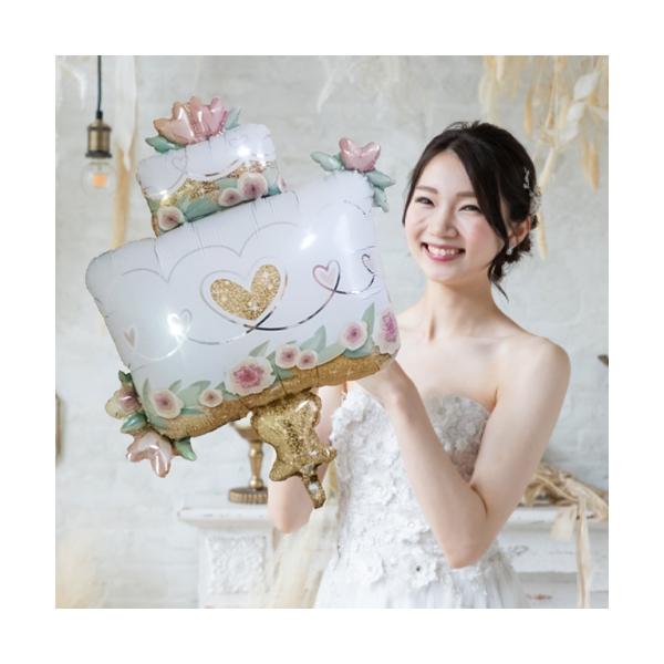 グリッタープリントのウエディングケーキ型バルーン（８０ｃｍｘ７０ｃｍ）は、ハートの飾りがとても可愛いデザインのバルーンです。結婚式や記念日に持って撮影したり、会場の装飾にもピッタリですよ。披露宴のテーブルサービスでゲストの皆さんと一緒に持っ...