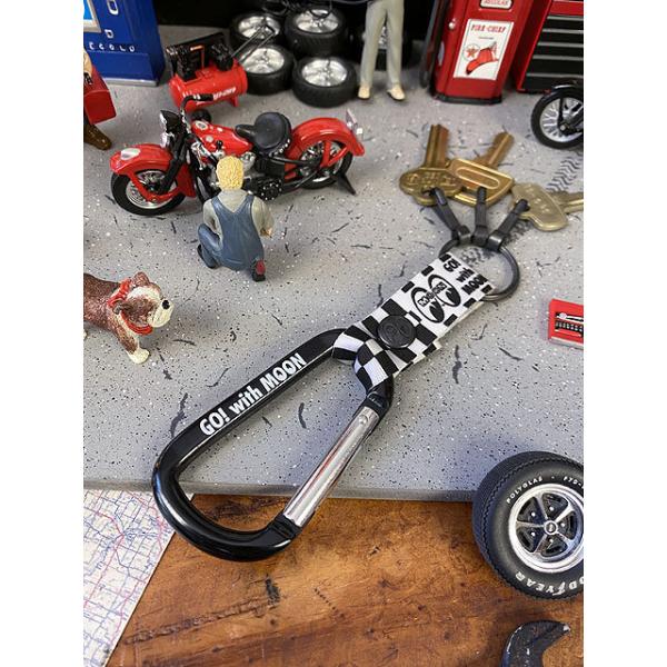 今やすっかりと定番アイテムとなったカラビナフックをムーンアイズブランドがプロデュース！ブラックベースのカラビナフックにムーンのスローガン「GO! WITH MOON」を入れチェッカーフラッグ柄のストラップでキーホルダーを留めたというデザイン...