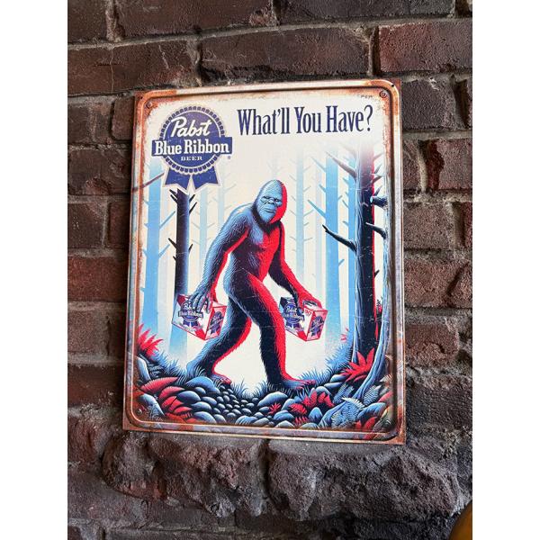 森の中でこっそり冷えたビールを運ぶ巨大な影。よく見るとそれ「ビッグフットがパブスト・ブルーリボンを抱えてる！」アメリカの老舗ビールブランド「PBR（パブスト・ブルーリボン）」が放つセンスしか感じないブリキ看板。上部のキャッチコピーは Wha...