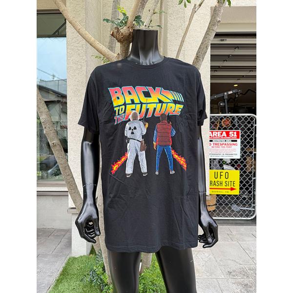 真夜中のツインパインズモールの駐車場に呼び出されたマーティと天才 発明家 ドクの伝説の名シーンがTシャツに！時速88マイルに加速したデロリアンが 白い光を放ちながら消え去りタイヤ跡の炎が燃えるあの名場面を タイトルロゴと共に描いた傑作です。...