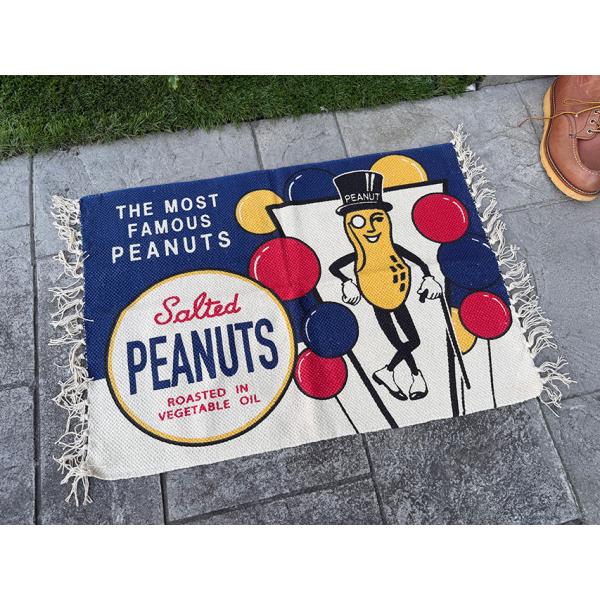 トップハットにステッキそしてあの独特のニヤリ顔。100年以上愛され続けるアメリカの象徴 “ミスターピーナッツ” を大胆にデザインしたコットン素材の室内用マットです。ネイビー × クリームの落ち着いた配色にどこかレトロな広告アートのようなグラ...