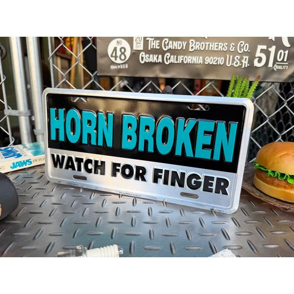 「ホーンがブッ壊れてるからオレの指を見な！」って書かれたこの看板、つまり中指立てて「ファ○ク・ユー！」ってこと！そんな強烈なブラックジョークをライセンスプレートで飾れるアメリカらしいデザインの1枚です。ホーンってだけに車のリアガラスから見え...