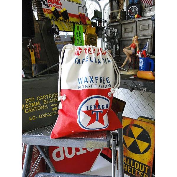 アメリカの直線道路を車で走ってると出会いそうなモーターオイルの看板がモチーフになったキンチャク袋です。子供の頃、これに上履きとか入れて学校に行ってましたよね！あの何でも入っちゃうキンチャク袋をモーター系デザインで格好良く仕上げたってのがコレ...