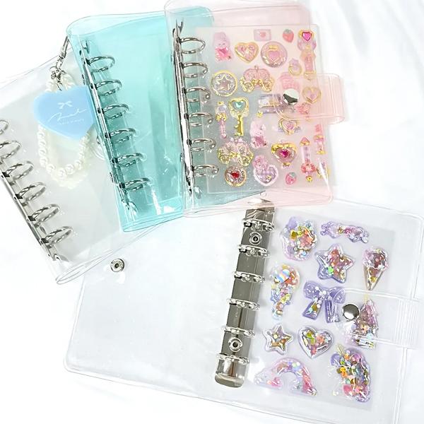 透明だから表紙を自分好みにアレンジできちゃう！PVC素材だから水濡れや汚れにも〇背表紙にはストラップホールが付いているので、お気に入りのチャームでデコれるのもポイントクリアシール台紙もたっぷり10枚入りですクリアタイプとラメ入りタイプで登場...