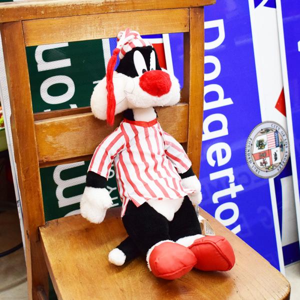 シルベスター・キャットのぬいぐるみが入荷！赤と白のストライプ柄パジャマにナイトキャップを合わせた、なんとも愛らしいおやすみスタイル。いつものいたずらっぽいシルベスターとはひと味違う、ユニークな姿が魅力です。アメリカン雑貨やヴィンテージトイの...