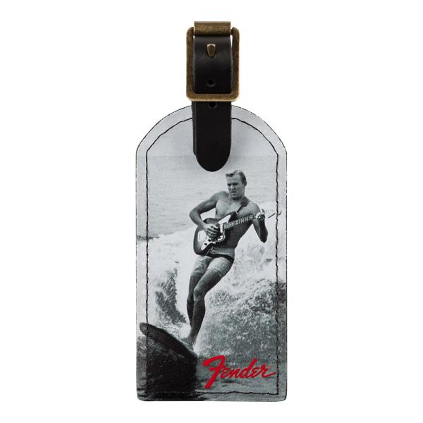 Fender フェンダー Vintage Ad Luggage Tag Surfer ラゲッジタグ  1960年初頭、モーターサイクル、スカイダイビング、そしてサーフィンなど、ありえないシチュエーションでギターを持ったミュージシャンが登場し...
