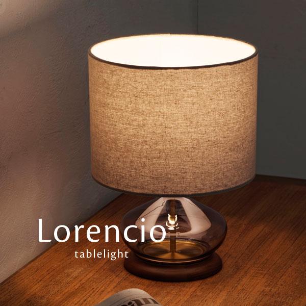 くびれのあるなめらかなプロポーションのガラスが優美なテーブルライト「ロレンシオ」。目にも心地よいファブリックシェードにブルーグレーのガラスが映えます。ファブリック、ウッド、ガラス、異素材をうまくまとめたおしゃれな1台です。■本体サイズ：直径...