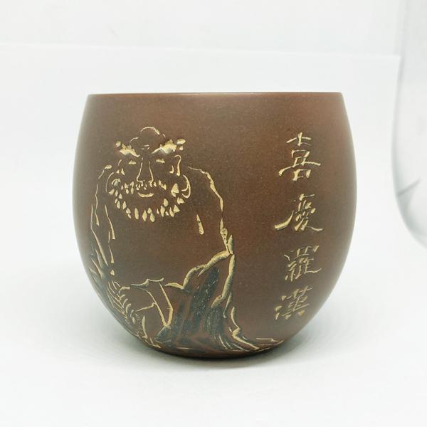 欽陶居工房　湯飲み  「喜慶羅漢」 十八羅漢杯十八羅漢の一人、迦諾迦伐蹉尊者、通称 喜慶羅漢です。ケガキは全て手彫りとなります。　分厚いためか重量感がありこの重さが好き！と言う方もおられます。鉄分を多く含む紫泥なのでとても固く頑丈でかつ、指...