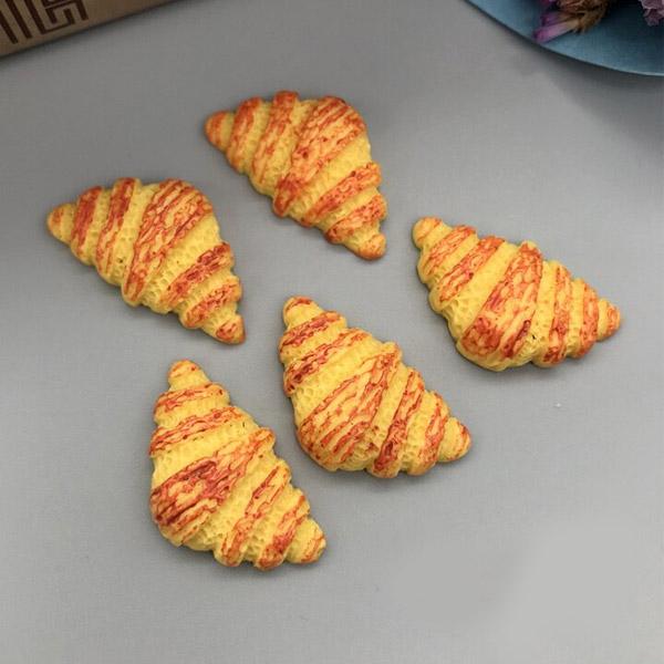 三角形なクロワッサンです！奇麗な焼き色でかわいらしいパーツに仕上がっています♪【販売単位】5個【サイズ】縦: 17mm, 横: 27mm【素材】プラスチック【ご注意点】入荷時期(ロット)によって多少色味が異なることがございます。ご覧いただい...