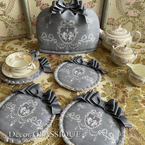 グレーのモアレプリントに天使とアンティークジュエリーをモチーフにした撥水加工プリント生地のティーコゼーとラウンドマットマットはポットマットとして、また カップ＆ソーサー用としてもおすすめですキルト綿入りでふっくらとした仕立てですサイズ : ...