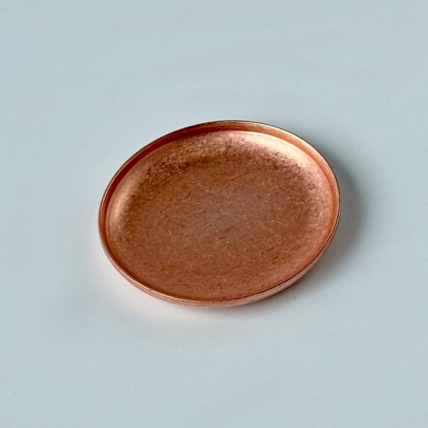 銅の素材感をいかし、加工で独特なざらつきと模様をつけた味わい深い趣のある直径4.5cmほどの豆皿です。ピアスやクリップを置いたり、小さなお香立てとしてもお使いいただけます。素材は銅無垢（丹銅）で、素地の風合いをそのまま活かしているのが特徴。...