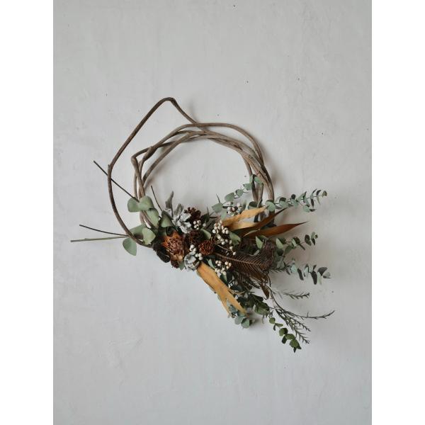 ユーカリをベースにグレビレアや木の実などを合わせて仕立てたドライフラワーリースです。ユーカリのやさしいグリーンとグレビレアの葉や木の実の自然な色合いが落ち着いたナチュラルな雰囲気を作ります。壁にかけて草花の景色として楽しめるドライフラワーリ...
