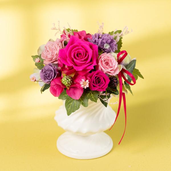 大切なお母さんへ。輝きを纏った「幸福」の贈り物「フェリーチェ」は、イタリア語で「幸せ」の意味。お母さんの幸せを願って贈りませんか？曲線美が際立つ脚付きの陶器製花器に、華やかなフューシャピンクのバラと、色とりどりのミニバラ、気品あふれる紫のカ...