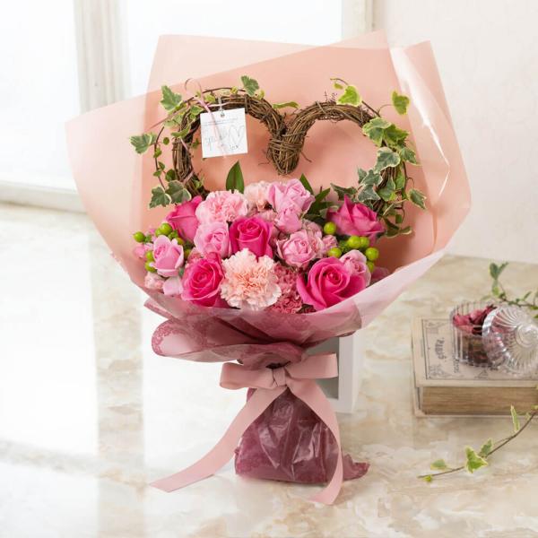 可愛らしいピンクの花々とハートのリースが印象的な花束。愛情、幸福などを象徴するハートをモチーフとしたリースに沿うようにあしらったアイビーには、「永遠の愛」「友情」「誠実」といった、人と人との絆や関係が途切れることなく、長く続くよう願った花言...