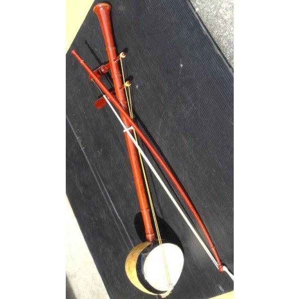 タイの伝統的な弓奏楽器です。本体の胴はヤシの殻の表面にヤギの皮が張ってあって、裏側には透かし彫刻が施されています。中国の二胡とも似ていますが、より低い音を奏で音色は独特です。タイの古典音楽クルアンサーイの合奏に用いられます。※ヤシ殻の色合い...