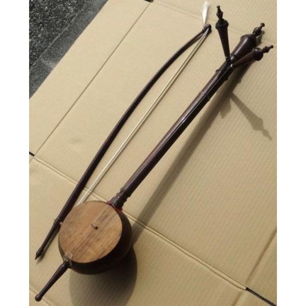 タイの伝統的な弓奏楽器です。チーク製の固いネックがヤシ殻の共鳴胴を突き抜けて作られています。弦を選ぶ時に弓に角度をつけるのではなく、楽器本体をクルリとまわしながら演奏します。サイズ−全長：約８１cm、幅：約１４cm、奥行：約２０cm