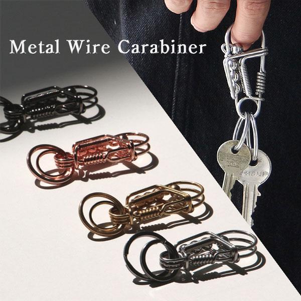 どこかスチームパンクのような雰囲気を持ち合わせた、１本の鋼線を曲げて仕立てたカラビナ。球体やコイルのパーツがインダストリアルなアクセントになりながらも、シャープな鋼線の繊細なディテールと溶け合うことで、クラシカルで遊び心のあるフォルムが性別...