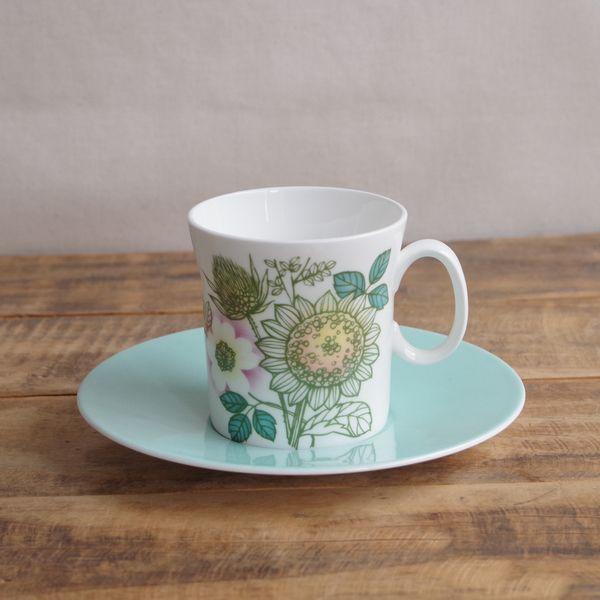 イギリスの陶磁器メーカー Hostess Tableware のカップ＆ソーサーです。Hi Summer というシリーズのものです。カップには、ひまわりや野ばらなど、レトロな花の絵柄が入っています。ソーサーは表側の面がきれいなターコイズブル...